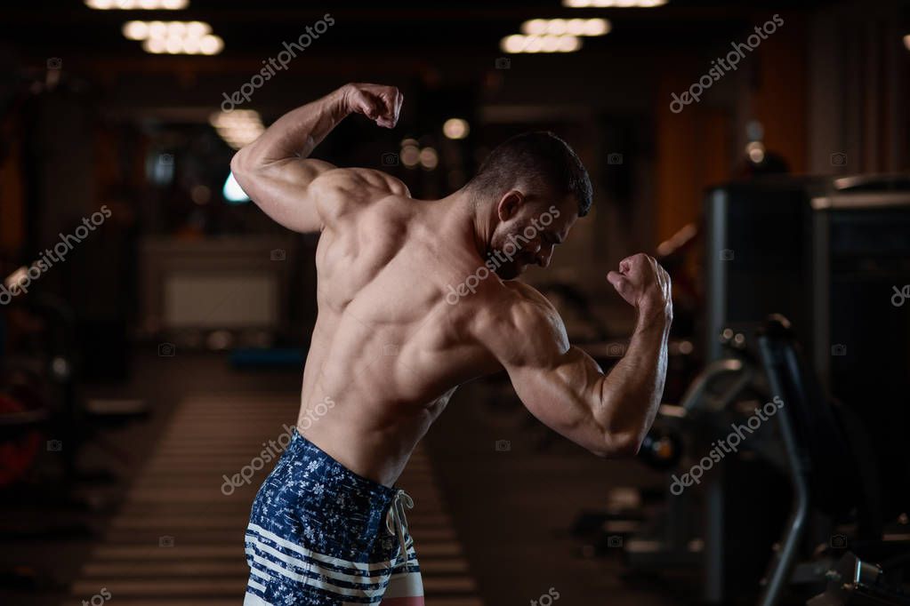 Un hombre atl tico brutal con un cuerpo muscular posa en el gimnasio, mostrando sus b ceps y ...