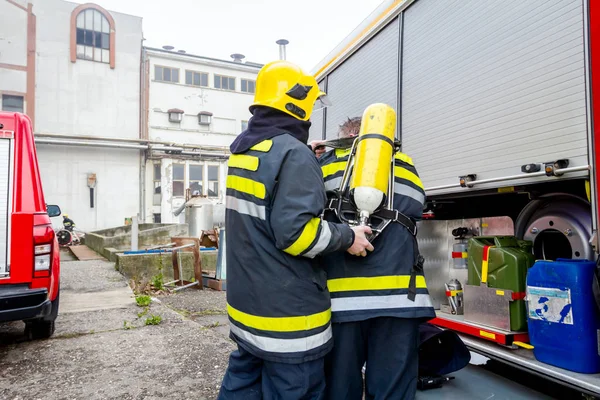 Firefighter is helping fellow to assembly his gear, keep balance and ...