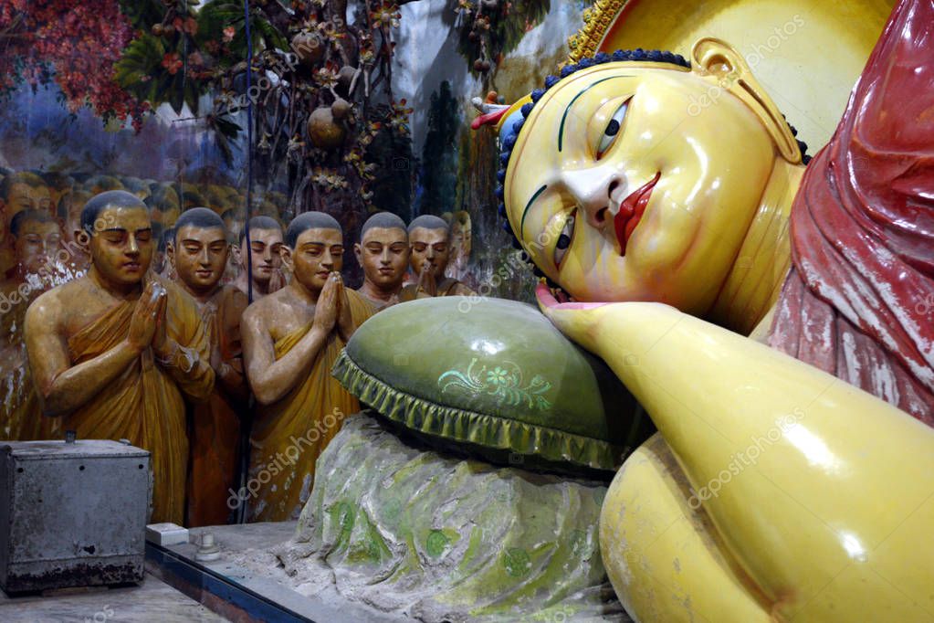 Las estatuas monje budistas rezan ante una estatua de Buda reclinada ...