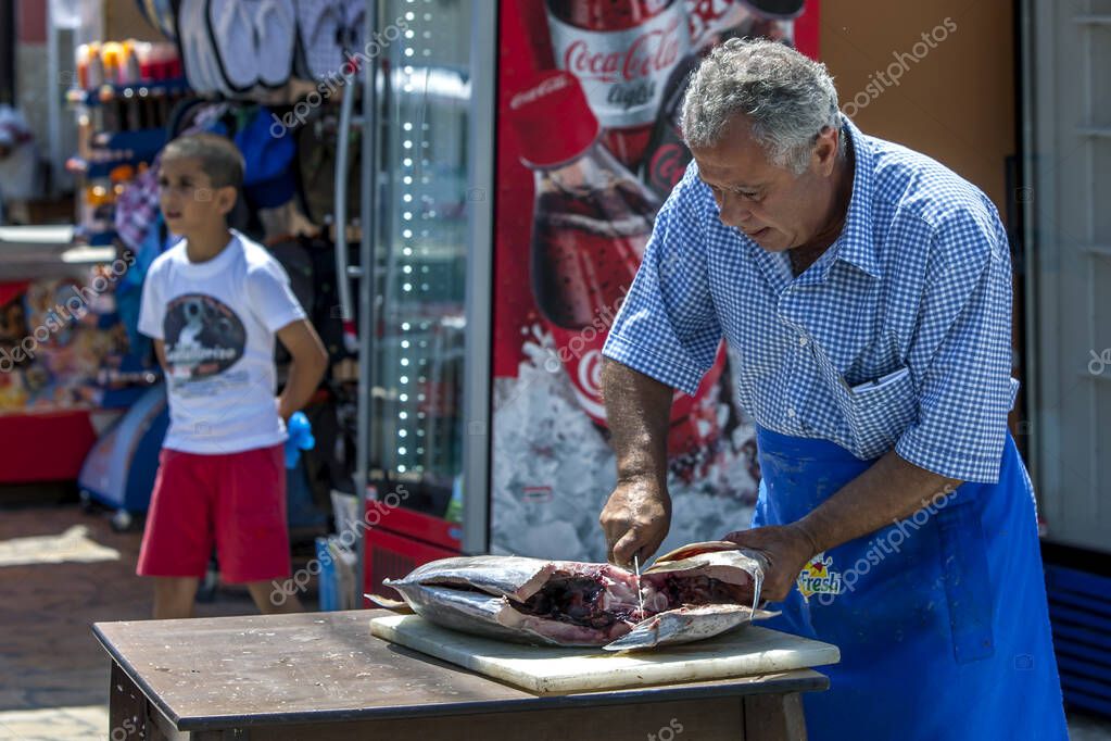 Un pescadero filete un pez en el puerto de la isla griega de ...