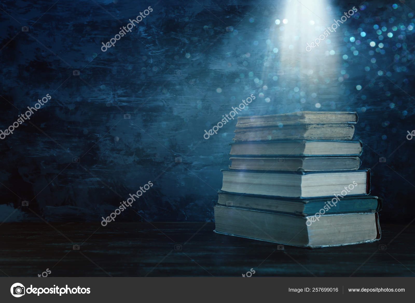 Stack of antique books with magical light on old wooden table. fantasy ...