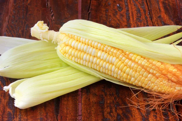 raw and fresh corn on the cob isolated on rustic wooden table. Copy ...