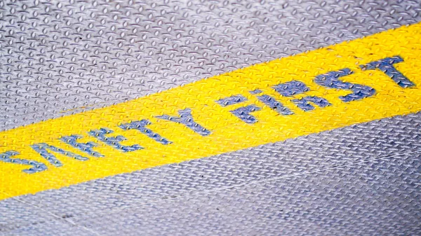 Safety first yellow label floor sign symbol on grey metal texture ...