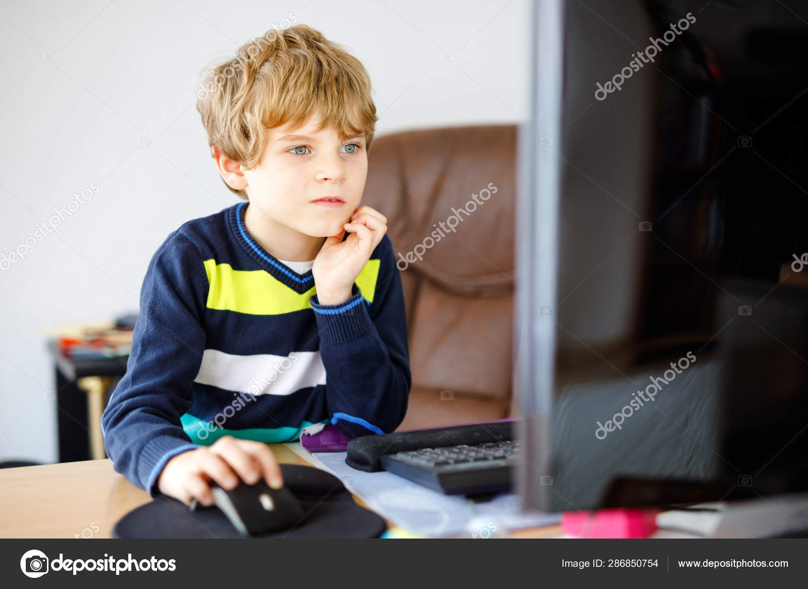 Little kid boy making school homework on computer notebook. Happy ...