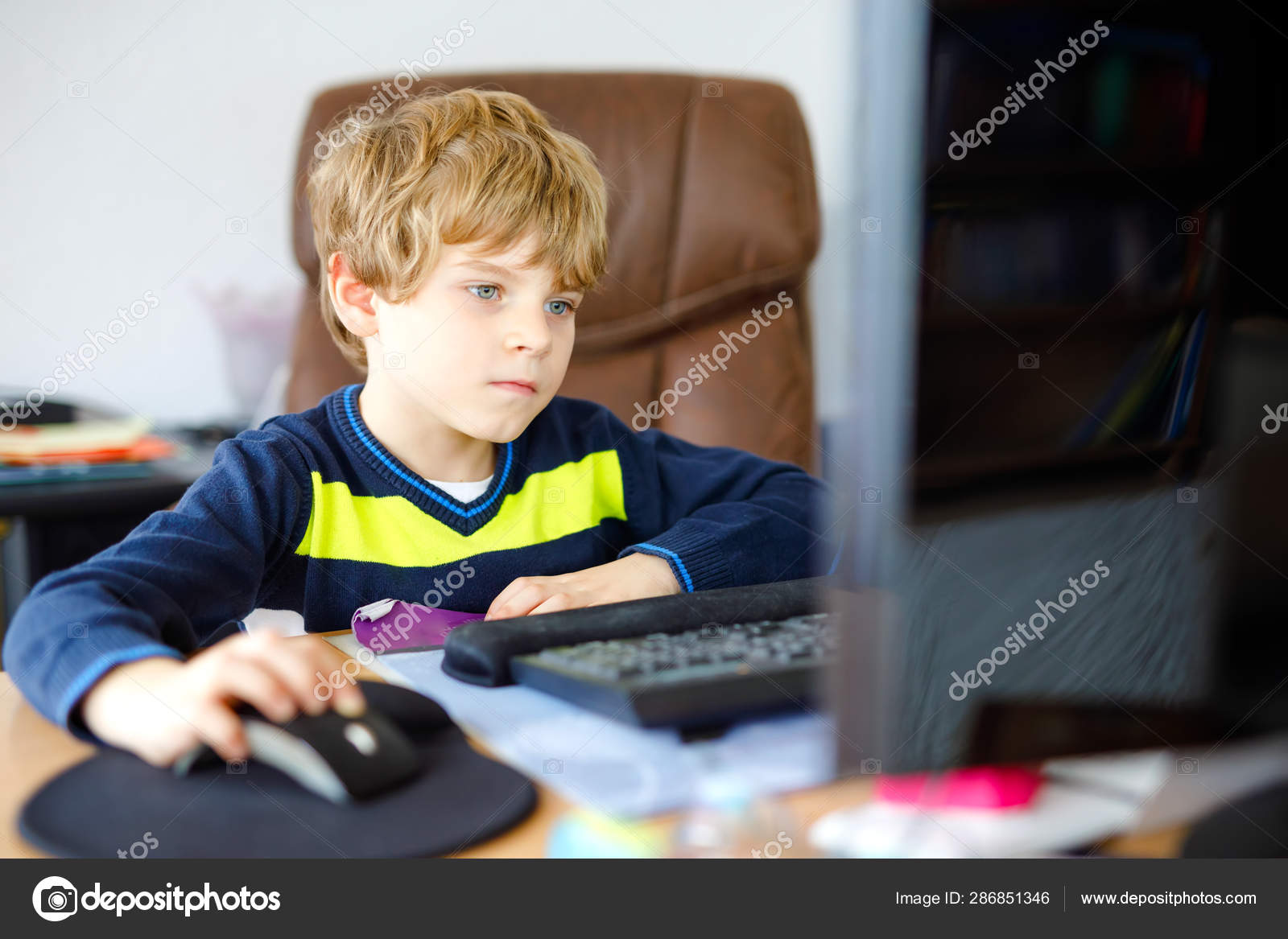 Little kid boy making school homework on computer notebook. Happy ...