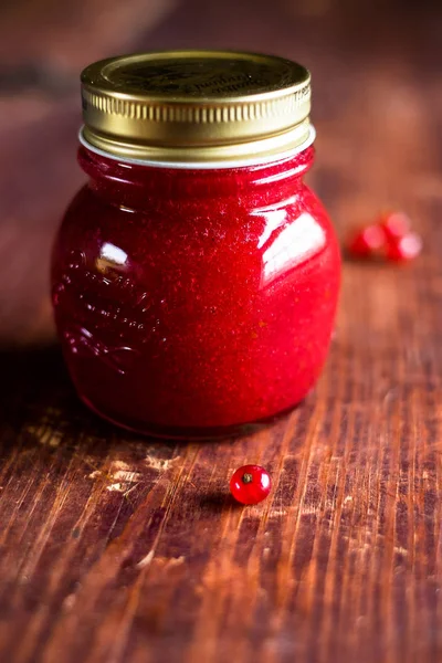 Jar of freshly made red currant jelly jam or sauce on a wooden table ...