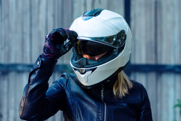 Woman puts on motorcycle helmet and fastens clasp - Stock Image ...