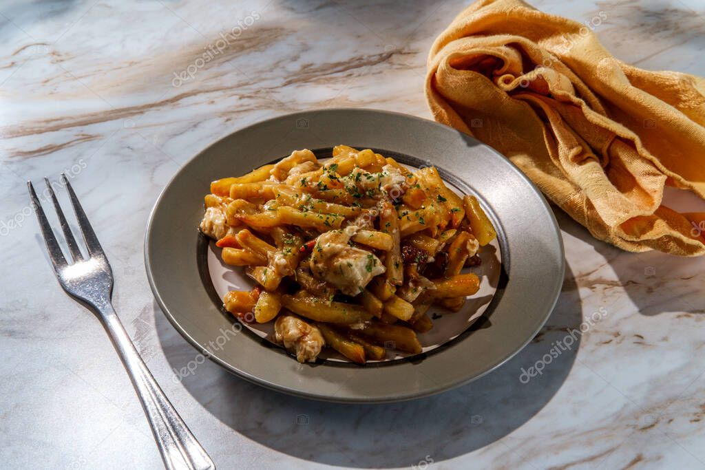 Papas fritas de poutine canadiense con salsa y queso cuajada en mesa de ...