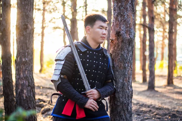 Warrior in black armor with a sword in his hands, is leaning against a ...