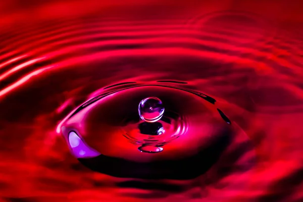 Close-up of a water droplets impacting water surface, resulting in a ...