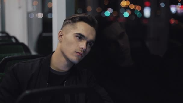 Sad unhappy man riding tram through the city at night. Depressed look ...