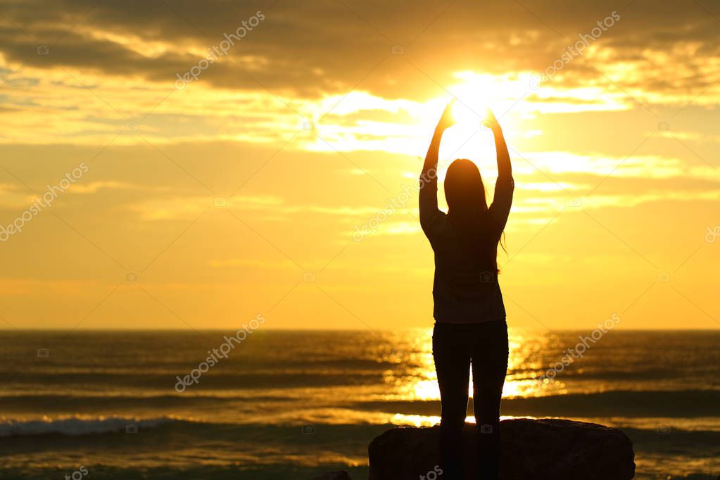 Vista posterior silueta de contraluz de una mujer que alcanza el sol al ...