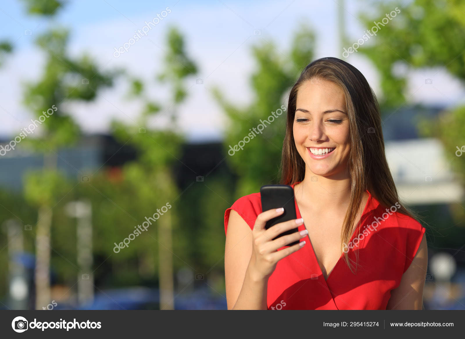 Happy woman in red checking phone text in the street Stock Photo by ...