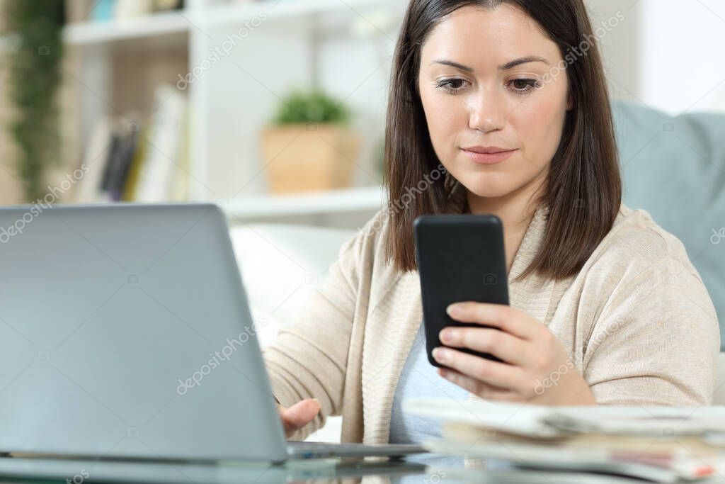 Mujer usando un port til y revisando un tel fono inteligente sentado en la sala de estar en casa ...