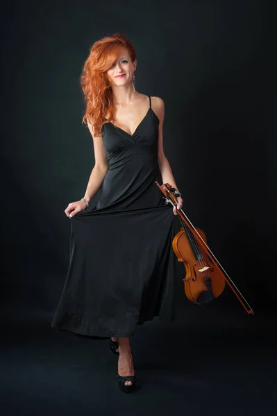 Young woman with violin against black background. Full body portrait ...