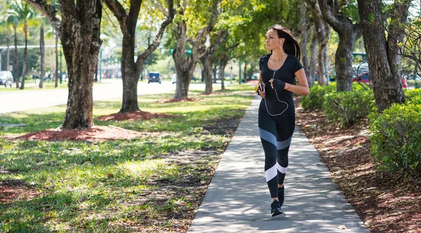 Young woman full body portrait running outdoors in a park in Miami ...