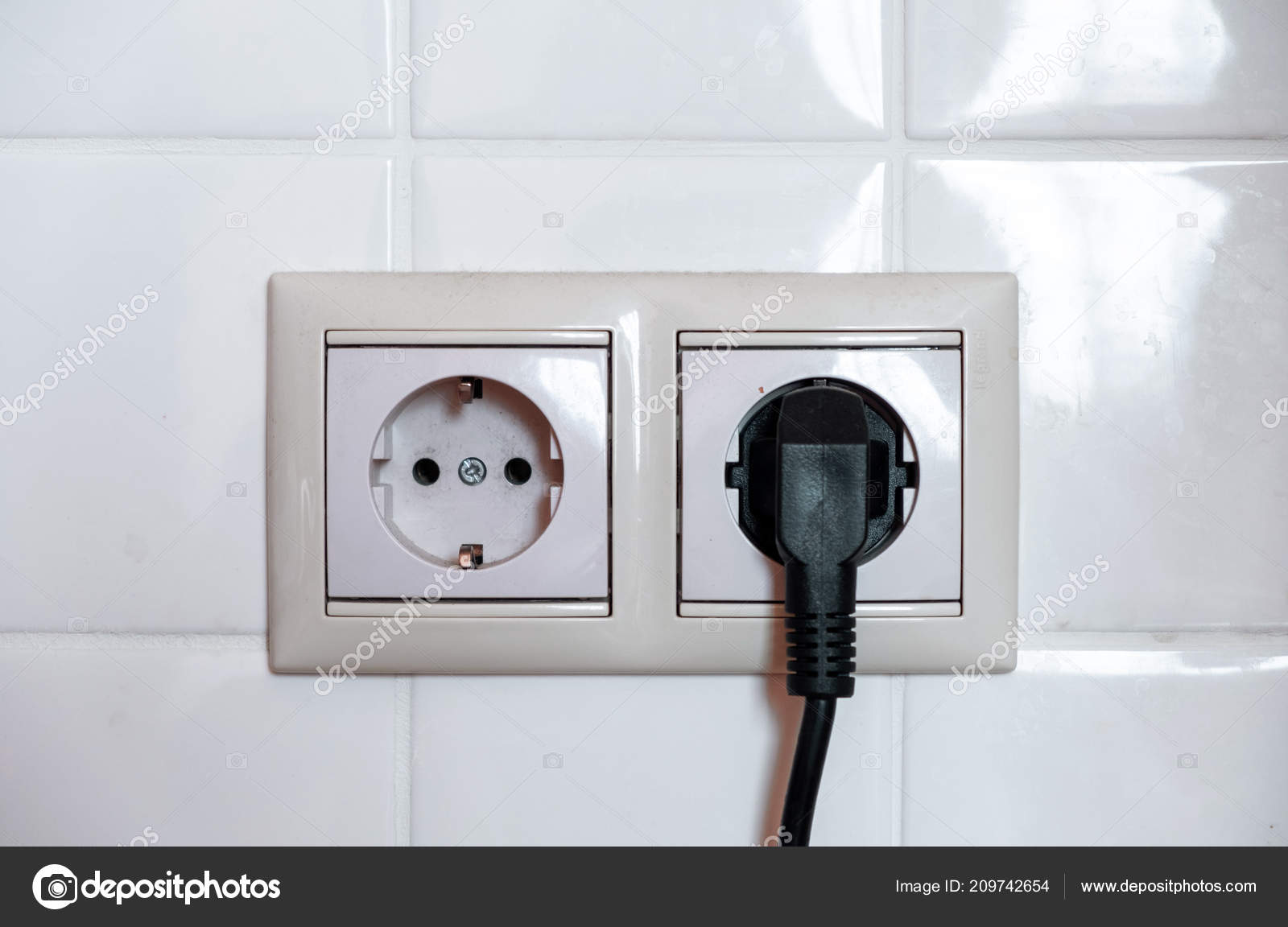 Electric black plug. Two sockets on a background of white tiles ...