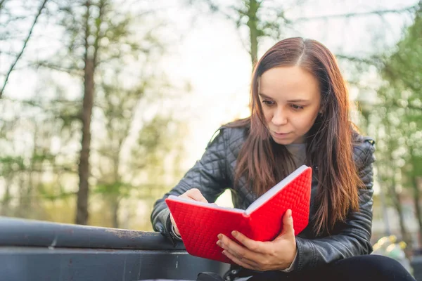Woman writing notes in red notebook on the street - Stock Image ...