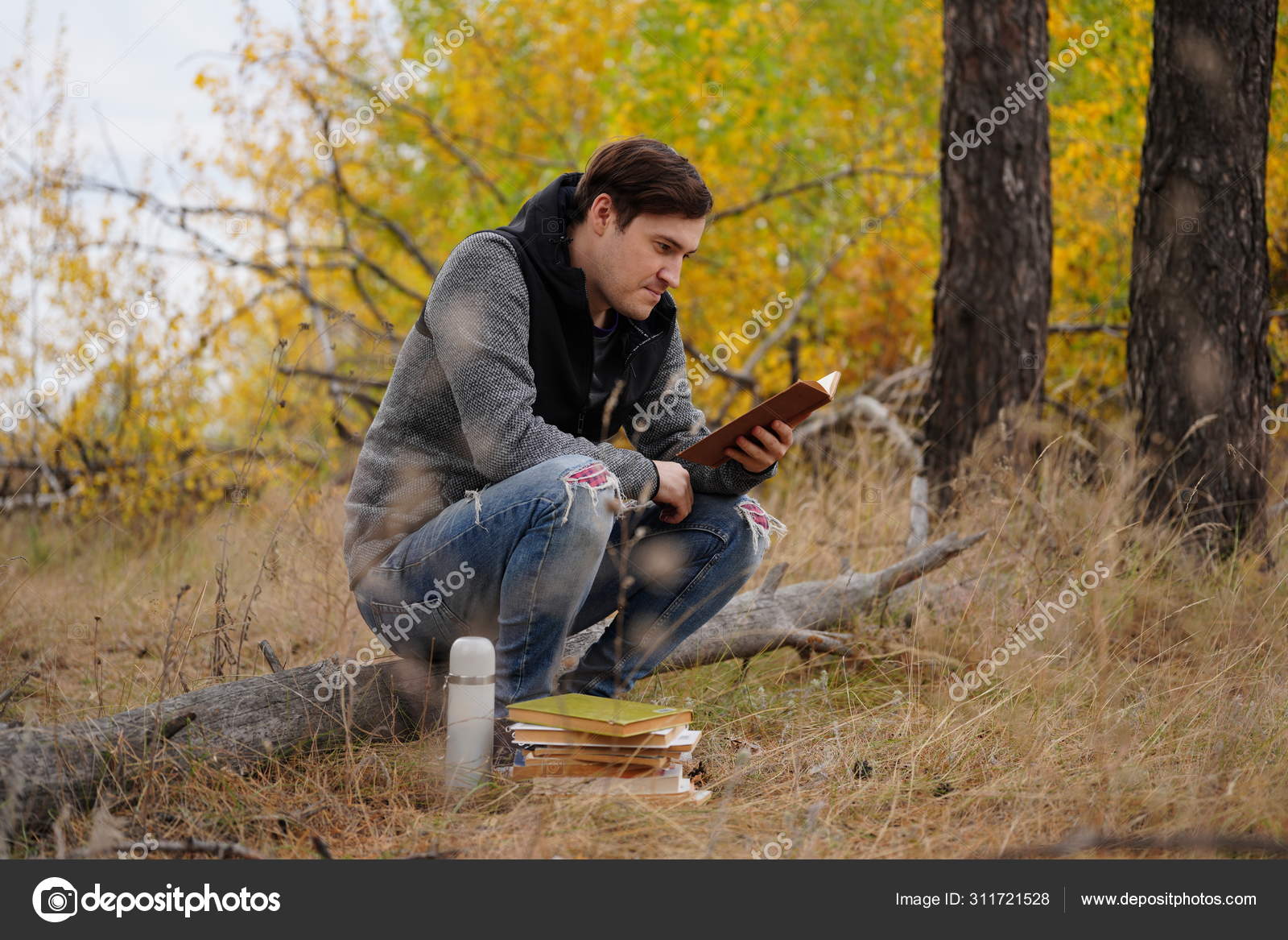 Beautiful man reading a book in the autumn forest. A man sits near a ...