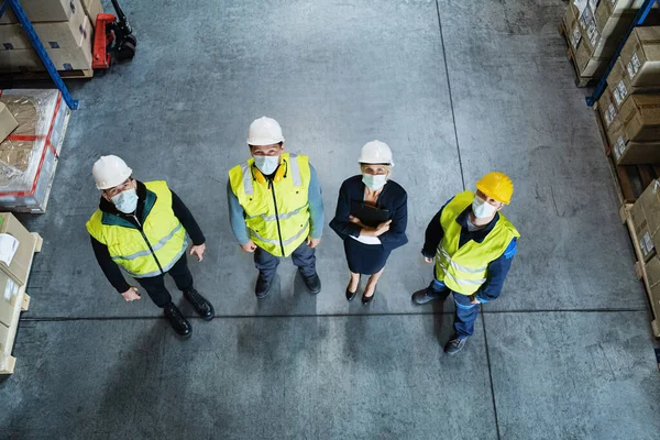 Top view of group of workers with manager indoors in warehouse ...