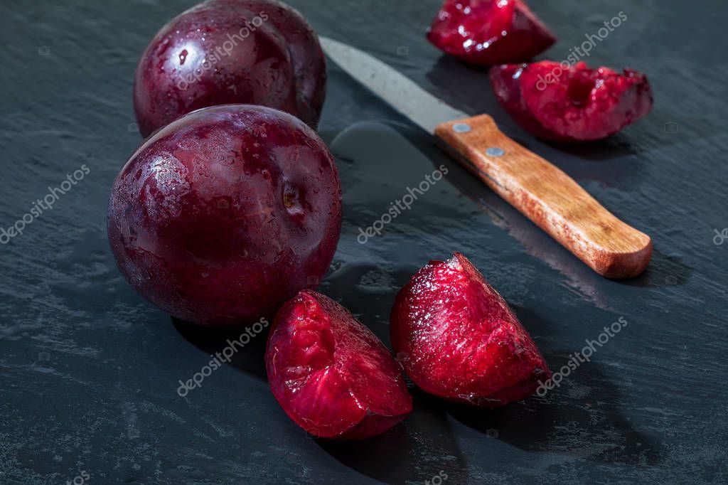 Ciruelas rojas apetitosas y sanas, enteras y cortadas en segmentos con ...