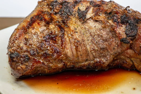 Trip tip Steak fresh off the grill and onto a white plate on the ...