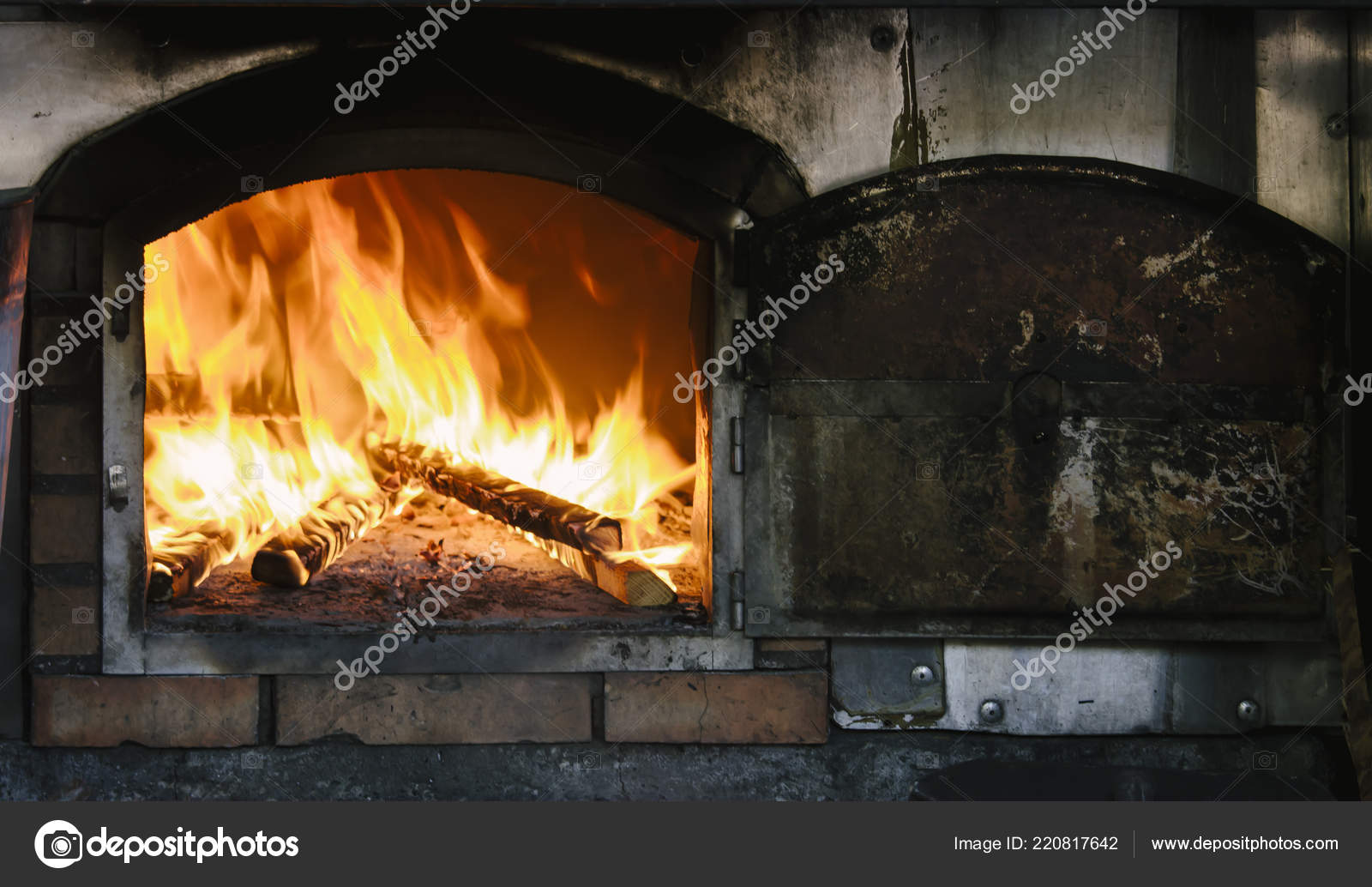Fire roaring and burning wood in traditional masonry oven, also known ...