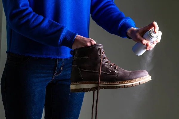 A person is cleaning and spraying agent on men's suede casual boots for ...