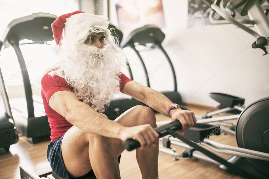 Santa Claus entrenamiento en máquina de remo después de las vacaciones ...