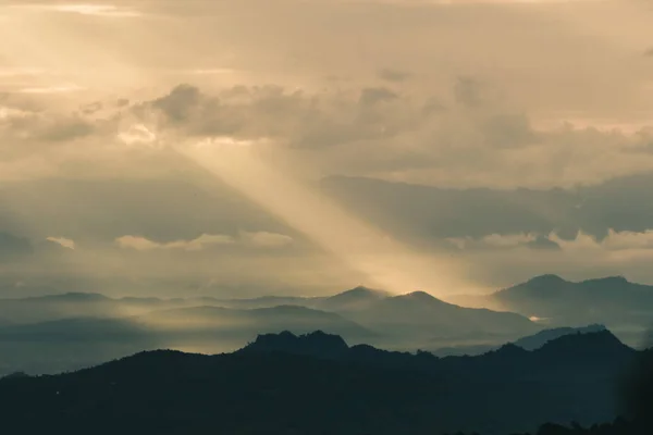 Beautiful sunrise in the mountains. Landscape with sun shining through orange clouds in Myanmar ...