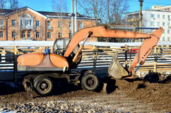 Excavator digging machine digs earth with stones with an iron ladle ...