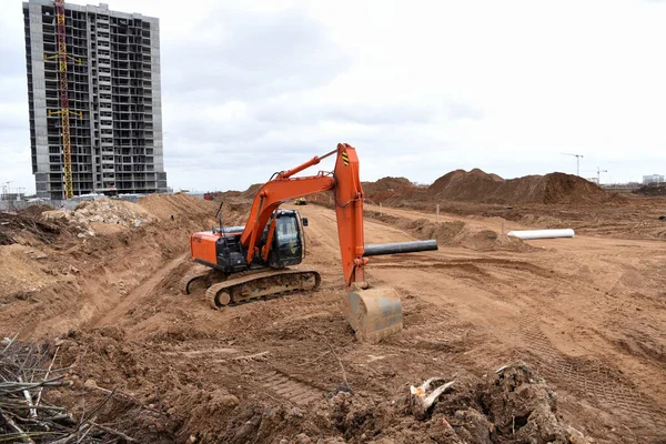 Red excavator during earthmoving at construction site. Backhoe dig ...