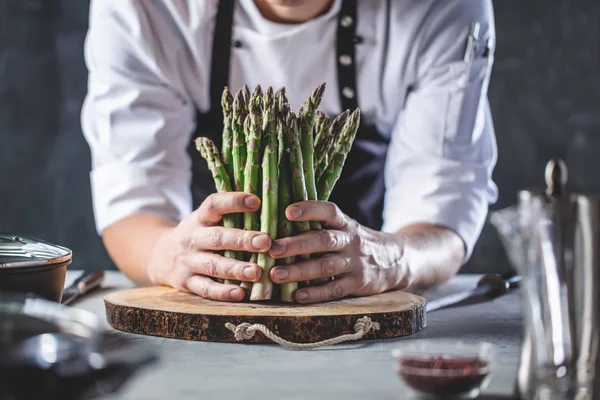 Green asparagus kept in men's Chef cook hands - Stock Image - Everypixel