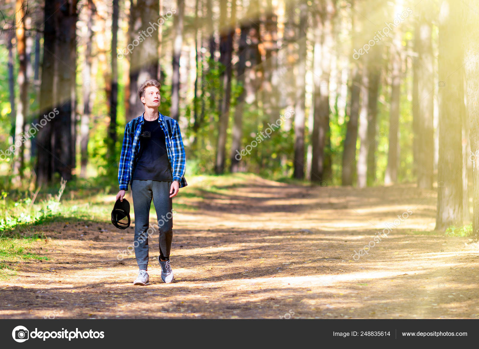 A young man with a cap in his hand is walking in a forest. — Stock ...