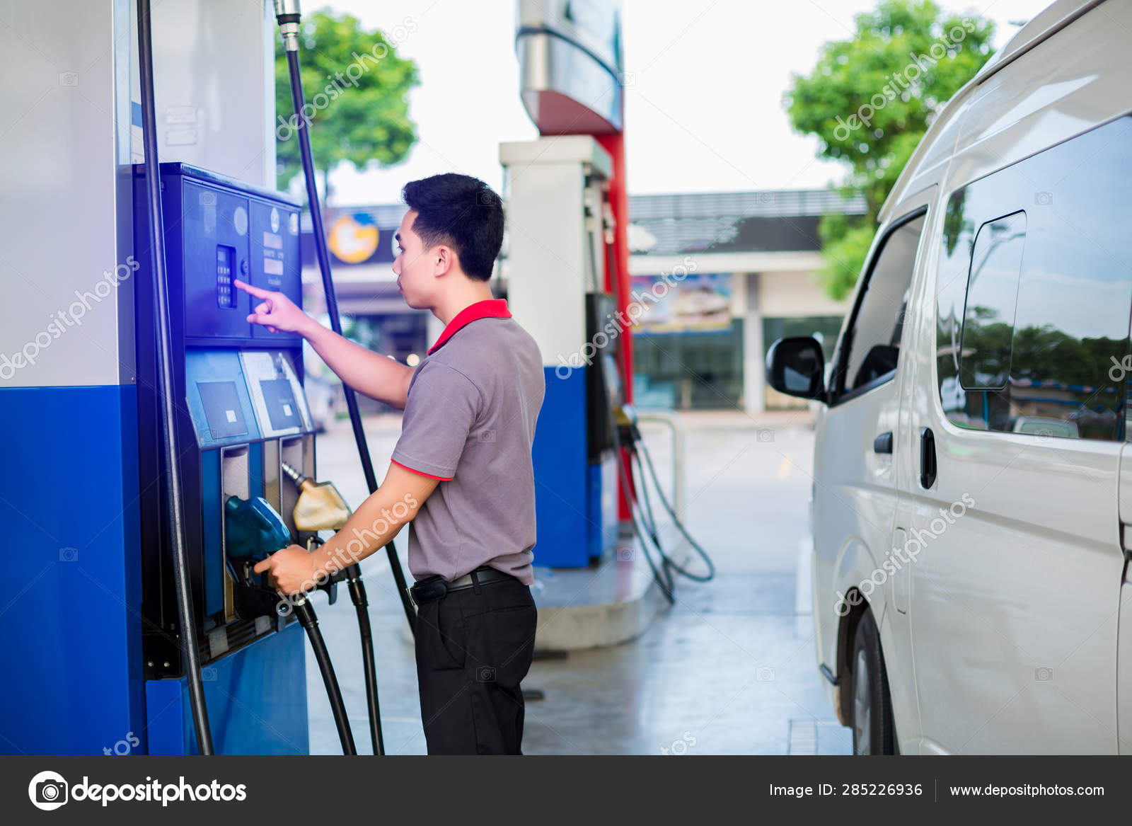 Selective focus to Asian staff is providing fueling services to — Stock ...