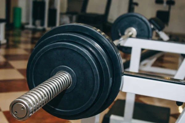 bar for power lifting with metal discs lies on the rack in the gym ...