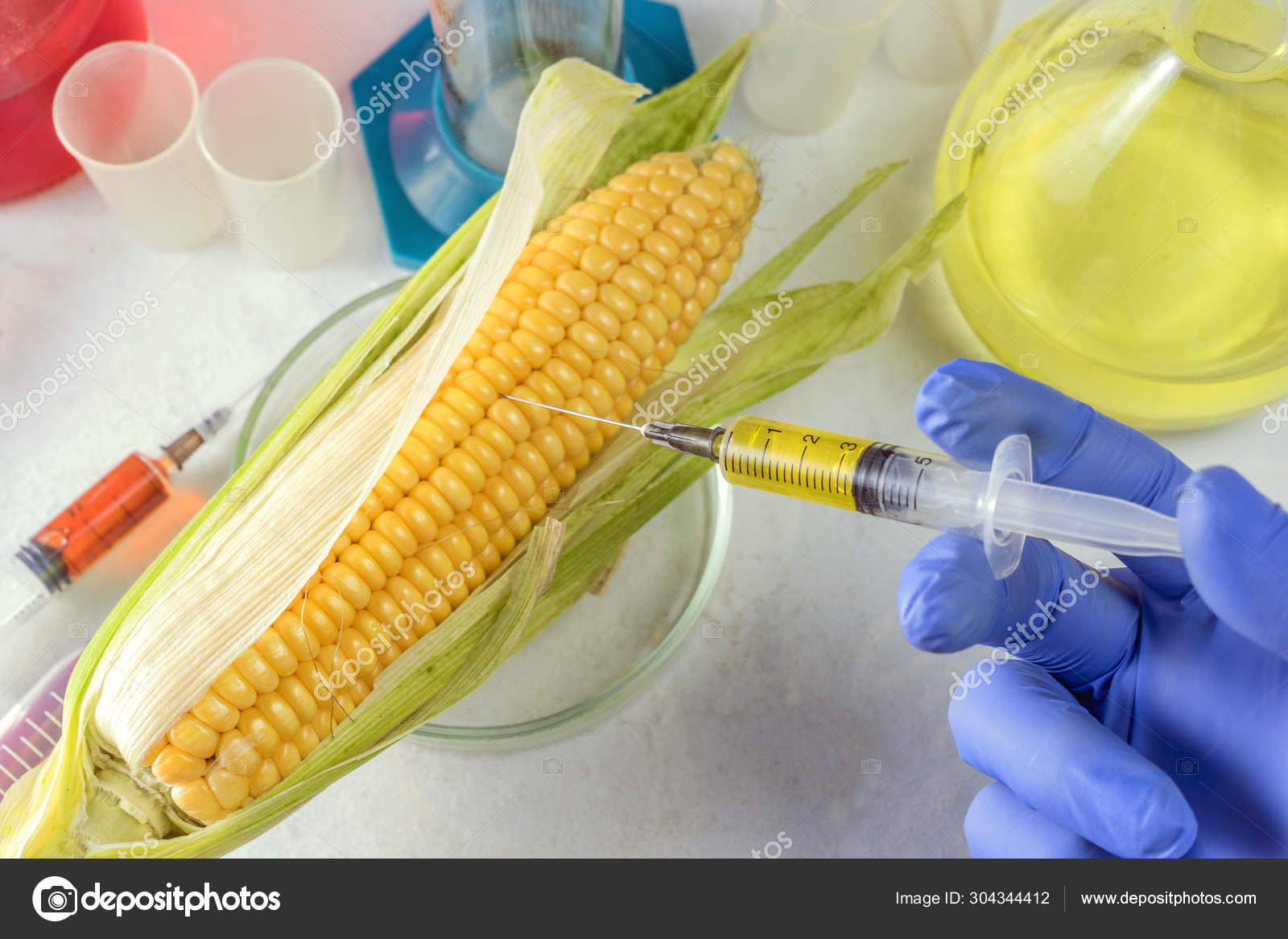 Hand with syringe and corn on lab table — Stock Photo © MichaelAbramov #304344412