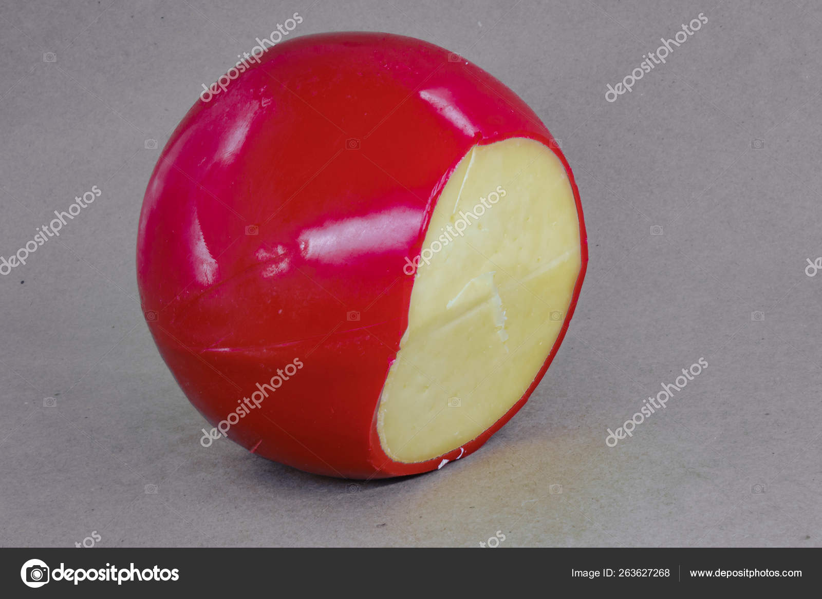 Wheel of fresh gouda cheese with a red rind on a gray monophonic ...