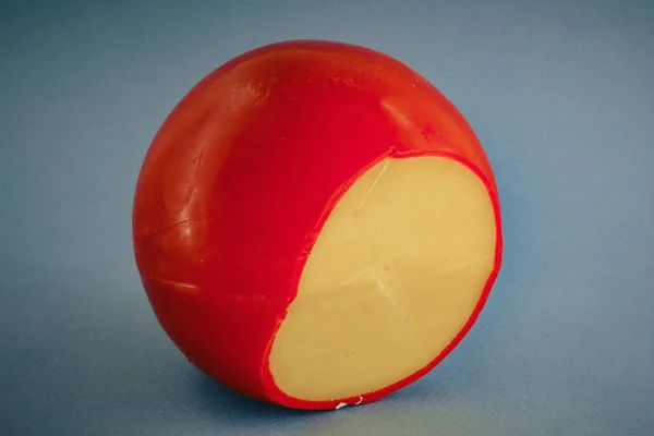 Wheel of fresh gouda cheese with a red rind on a gray monophonic ...