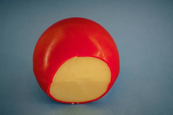 Wheel of fresh gouda cheese with a red rind on a gray monophonic ...