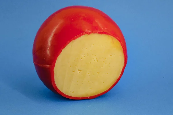 Wheel of fresh gouda cheese with a red rind on a gray monophonic ...