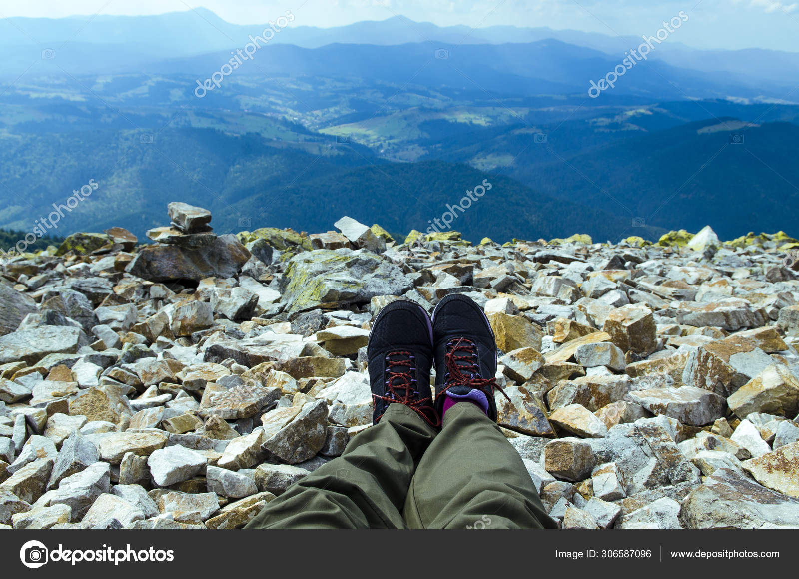 Mans legs in tracking sneakers on top of the mountain against the ...