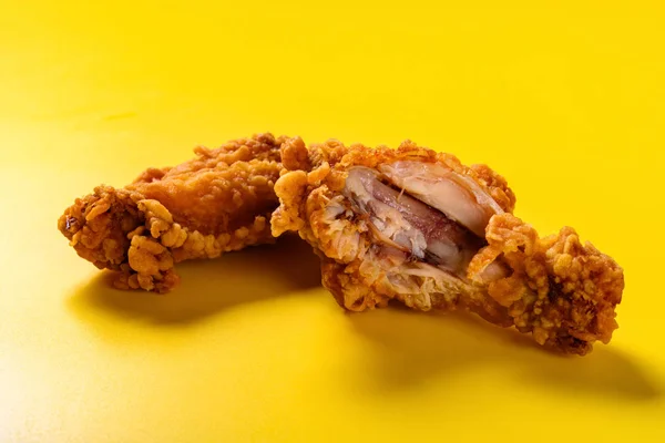 side view fresh deep fried chicken drumstick and wing with a bite on ...