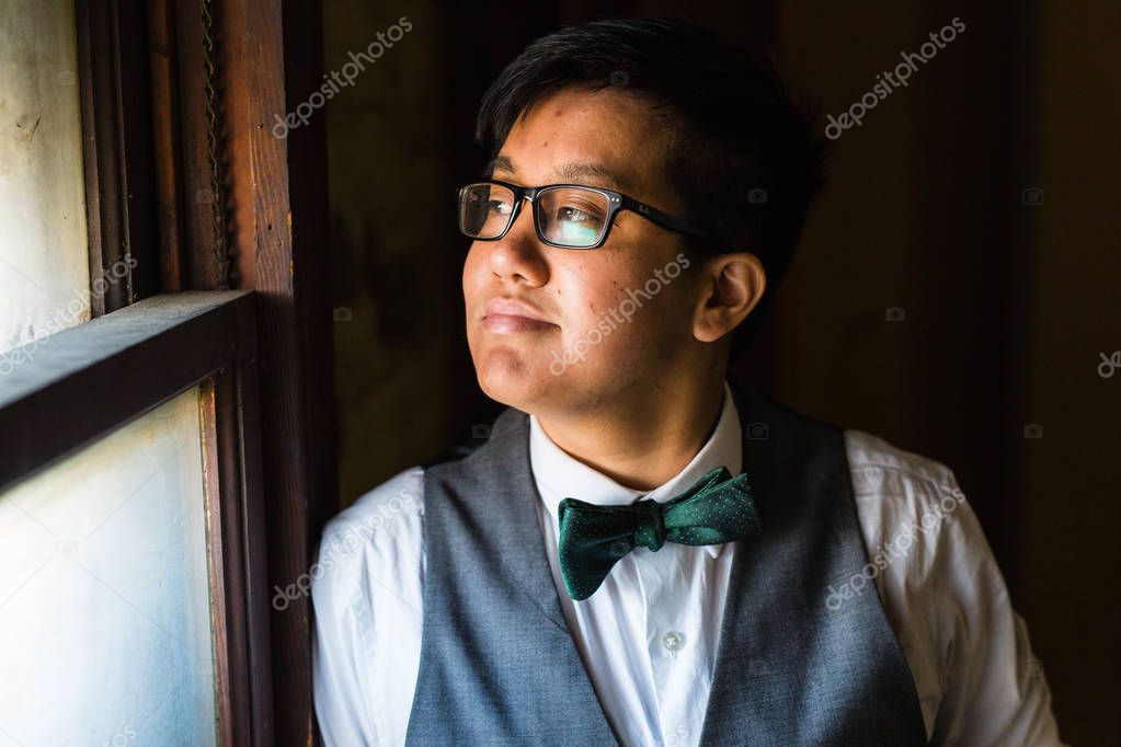 Joven hombre transgénero en ropa formal posa en una ubicación urbana ...