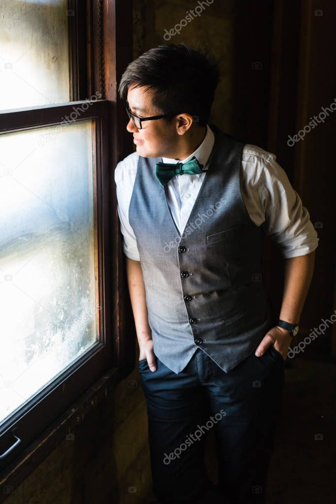 Joven hombre transgénero en ropa formal posa en una ubicación urbana ...