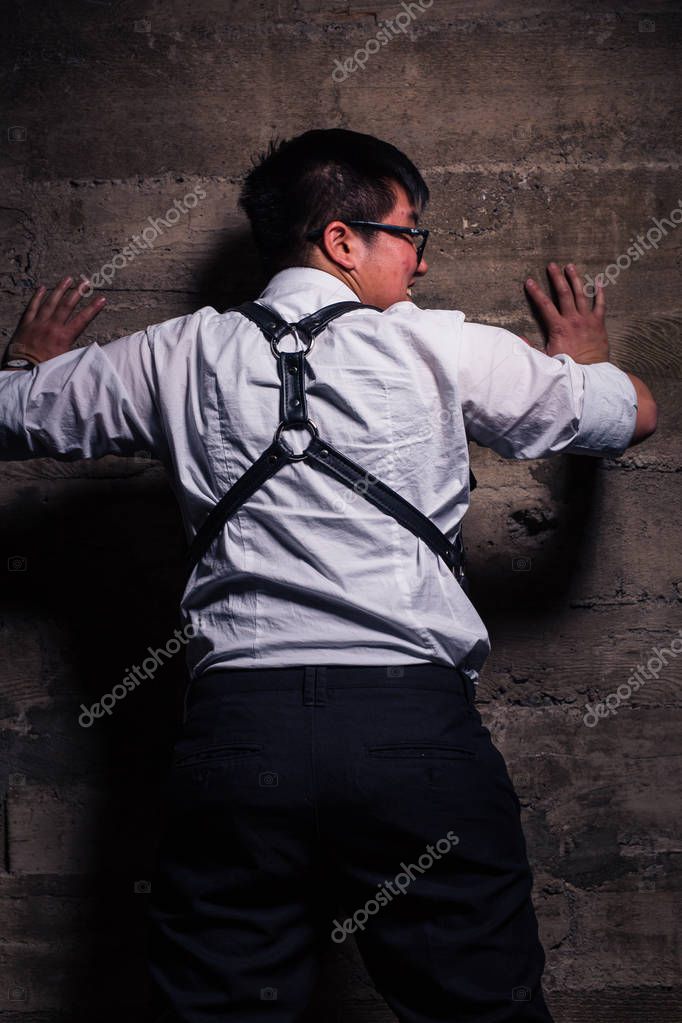 Joven hombre transgénero en ropa semi formal con un arnés de cuero ...