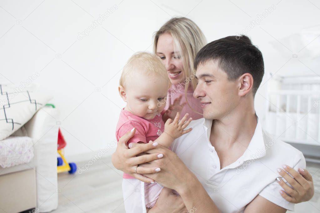 Sonriendo feliz joven madre y padre de pie en su sala de estar en casa cariñosamente acunando a ...