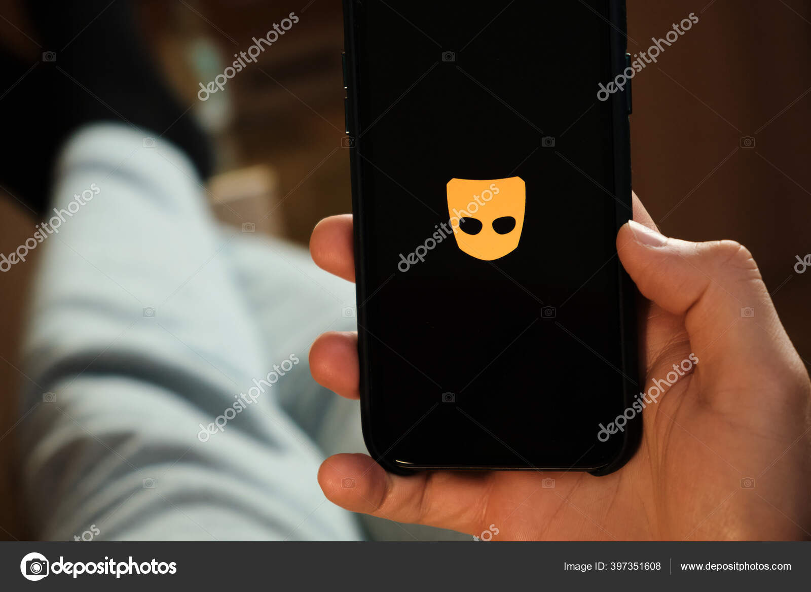 Grindr application on the smartphone in mans hand. Man laying and using ...