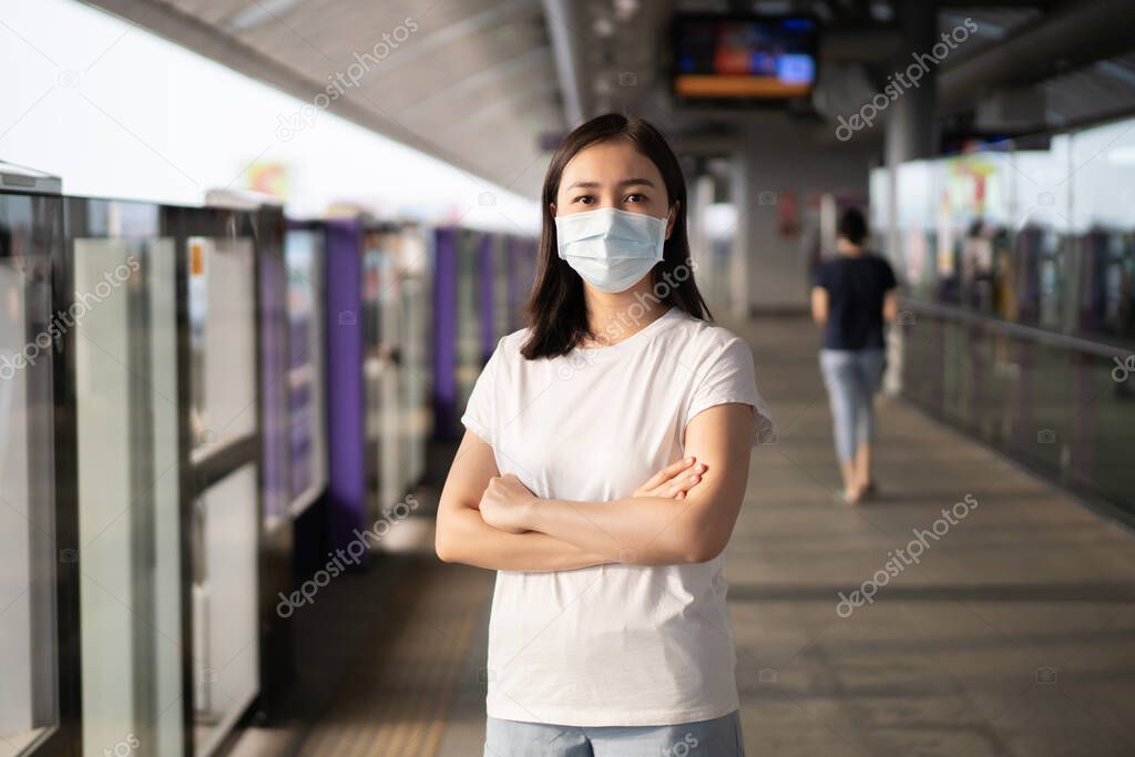 Hermosa mujer asiática joven que lleva la máscara protectora mientras ...