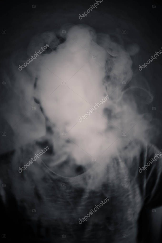 Hombre irreconocible en la nube de humo de vapor. Un tipo fumando ...